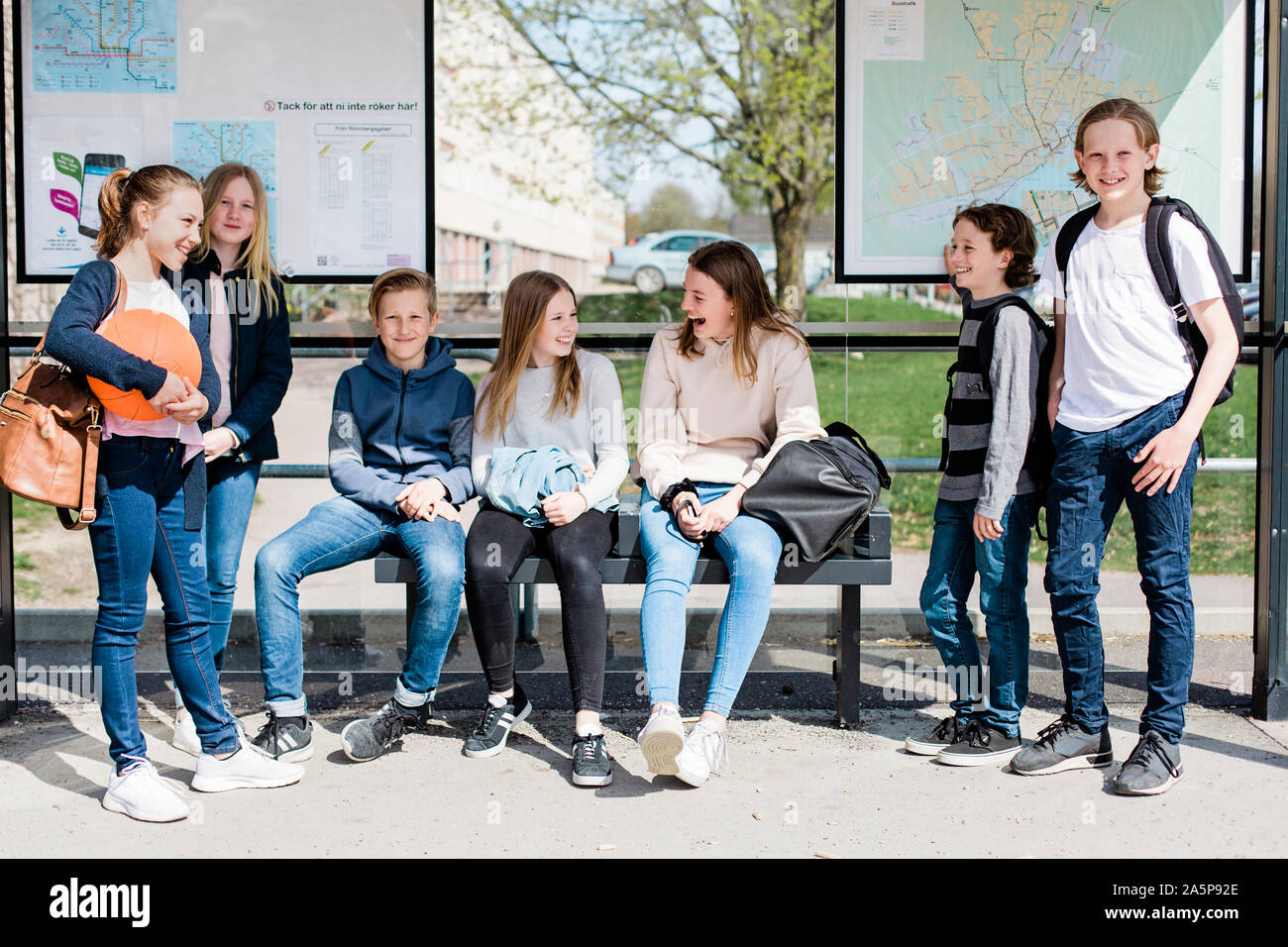 Boys and girls on bus stop Stock Photo - Alamy