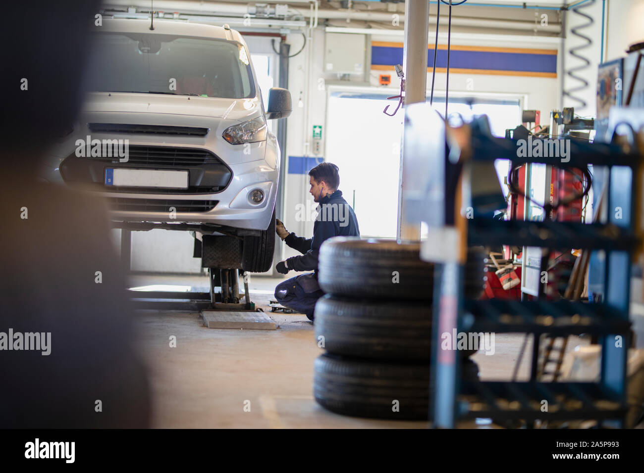 Man changing wheel in garage Stock Photo - Alamy