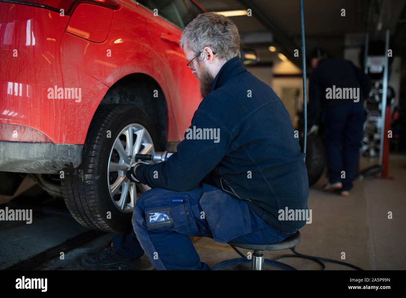Man changing wheel in garage Stock Photo - Alamy