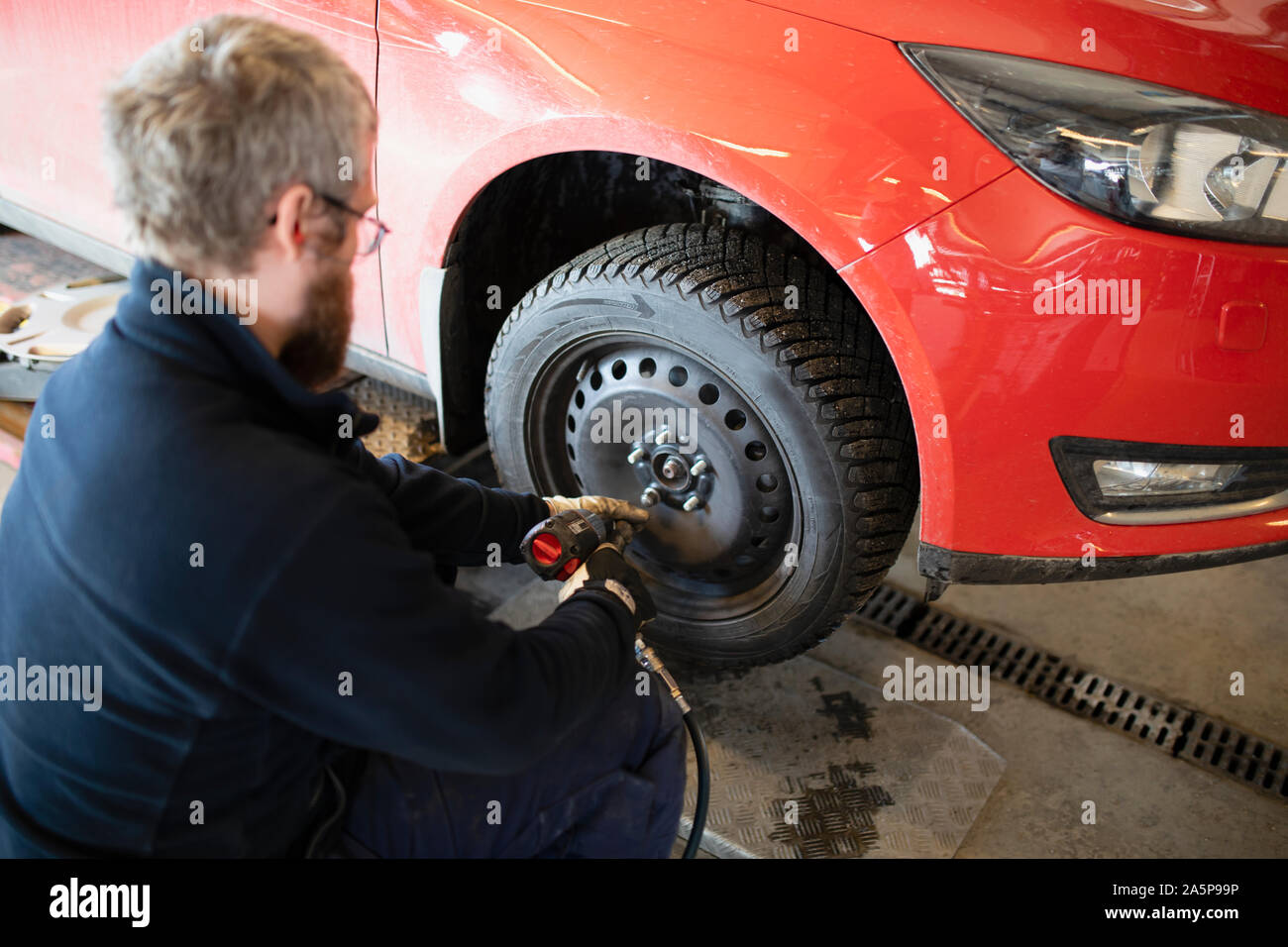 Man changing wheel in garage Stock Photo - Alamy