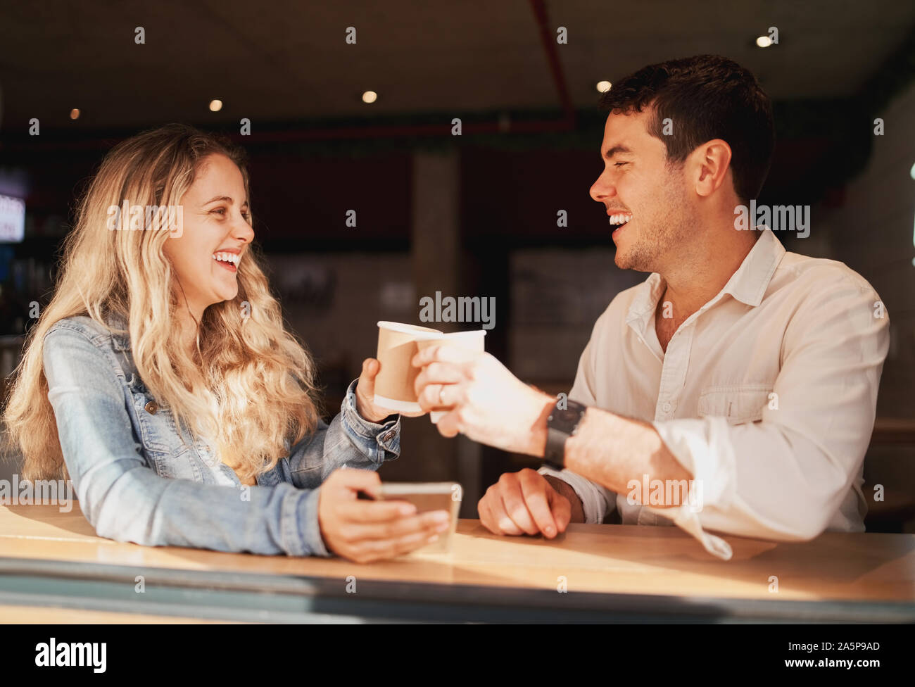 Smiling young friends in a coffee shop spending time together toasting ...