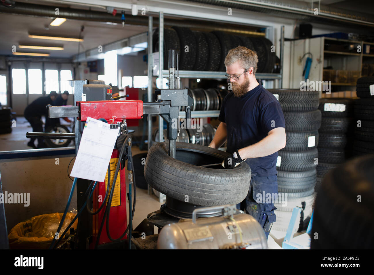 Mechanic in garage changing tire Stock Photo - Alamy