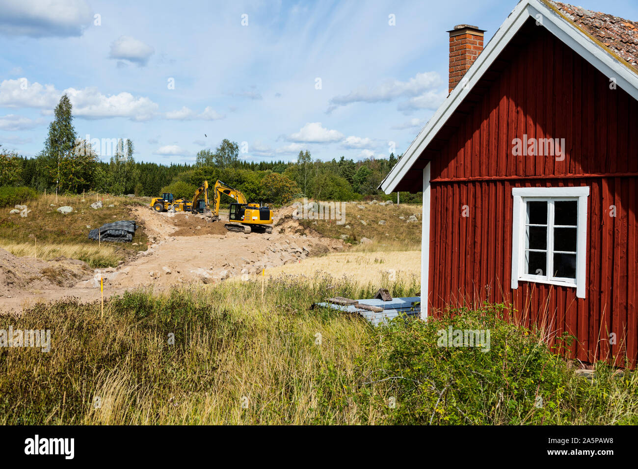 Wooden house, digger at work on background Stock Photo - Alamy