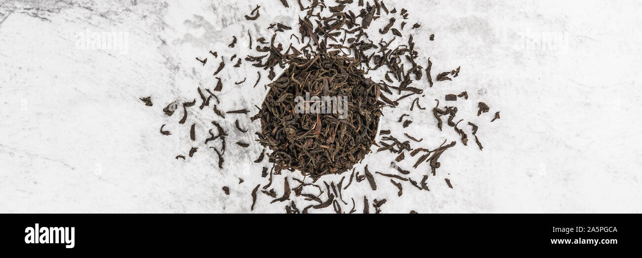 Dried tea is poured into a white ceramic cup on a marble table. View ...