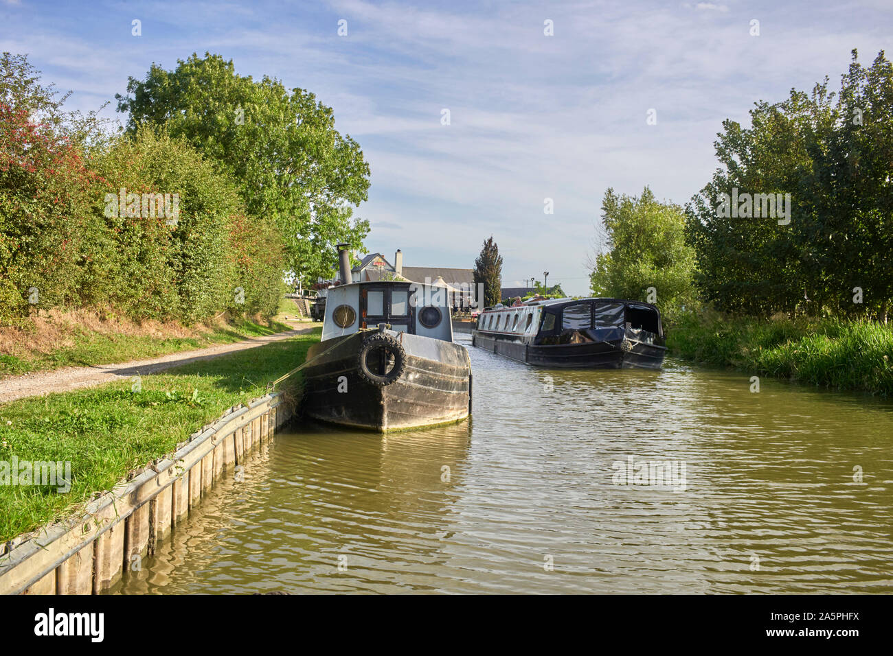 A widebeam canal boat passing a moored narrowboat showing how wide ...