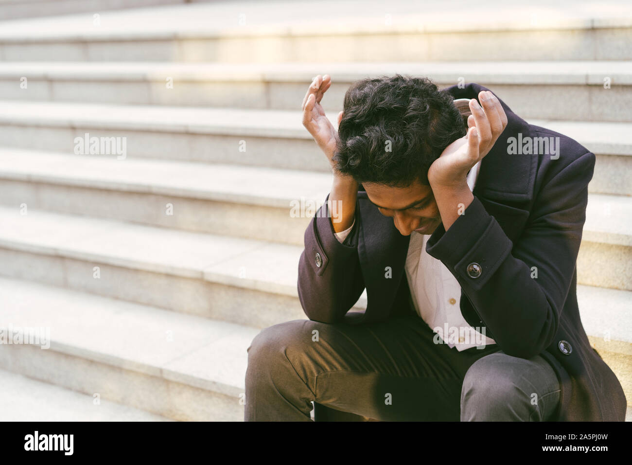Young handsome Indian man. Sitting sad on the steps Stock Photo - Alamy