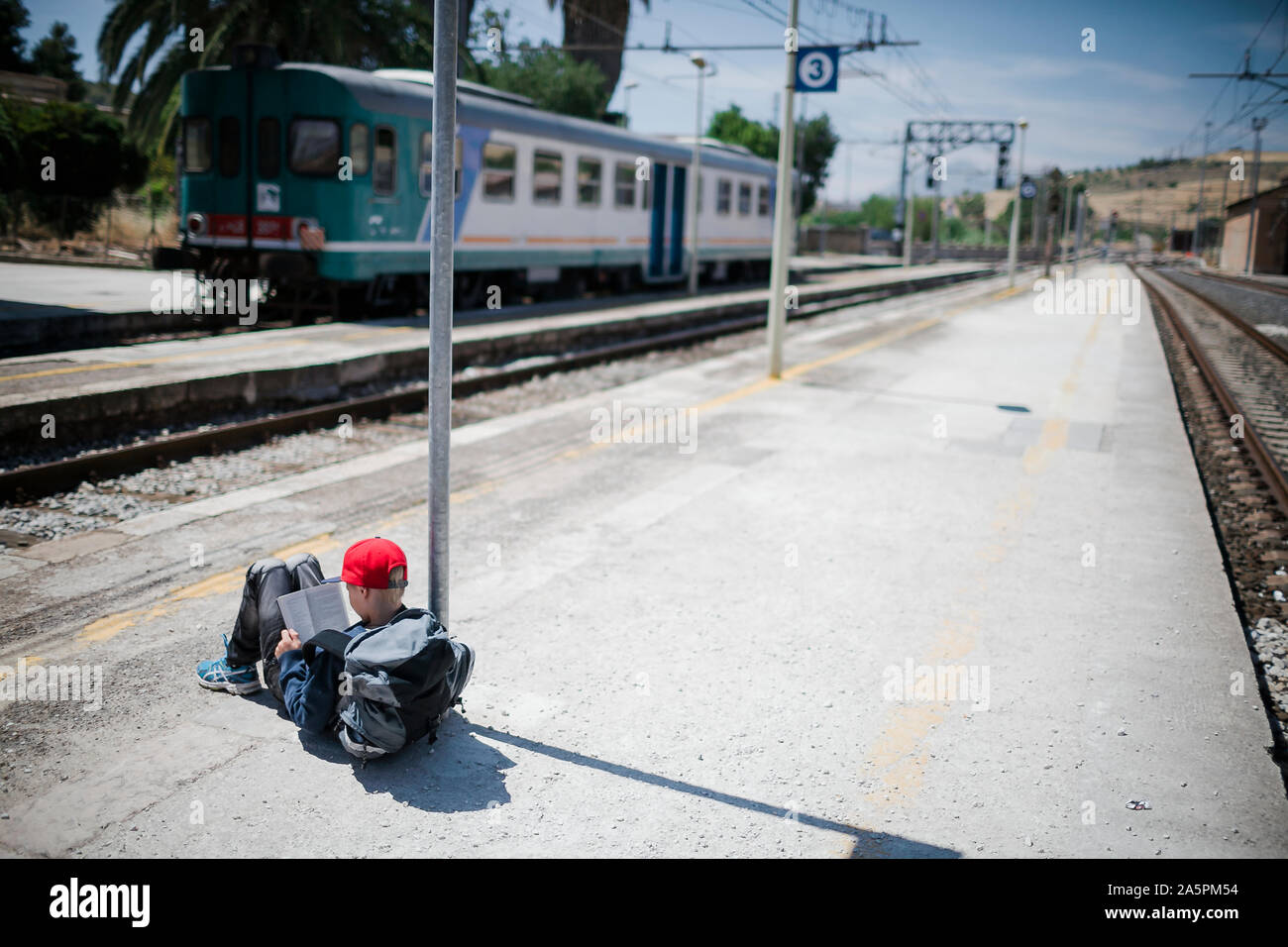 Boy reading on train platform Stock Photo - Alamy