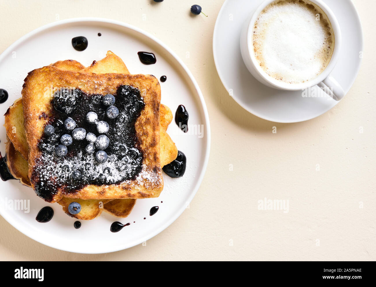 French toasts with blueberry sauce and cup of coffee on light stone ...