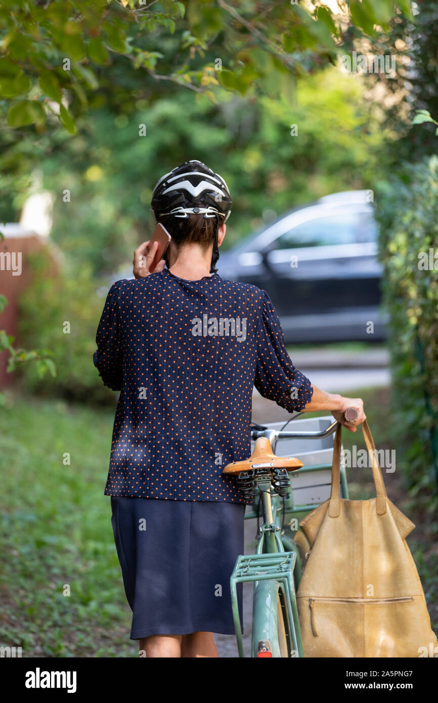 Woman pushing bike along road Stock Photo - Alamy