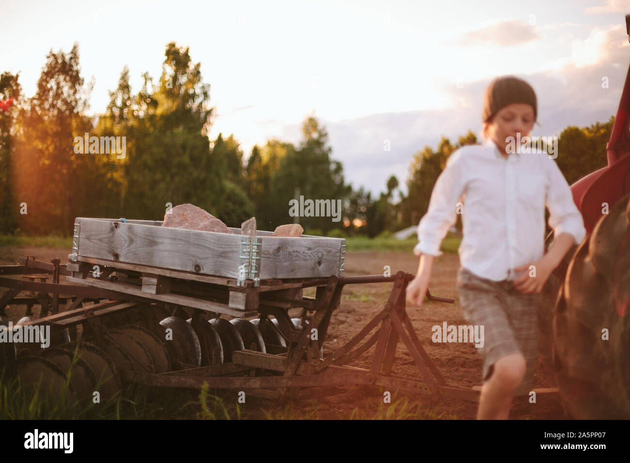 Boy standing near plow Stock Photo - Alamy