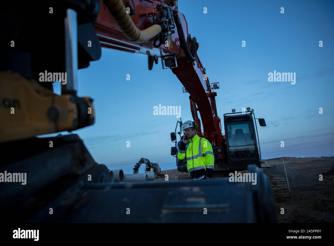 Worker in front of digger Stock Photo - Alamy
