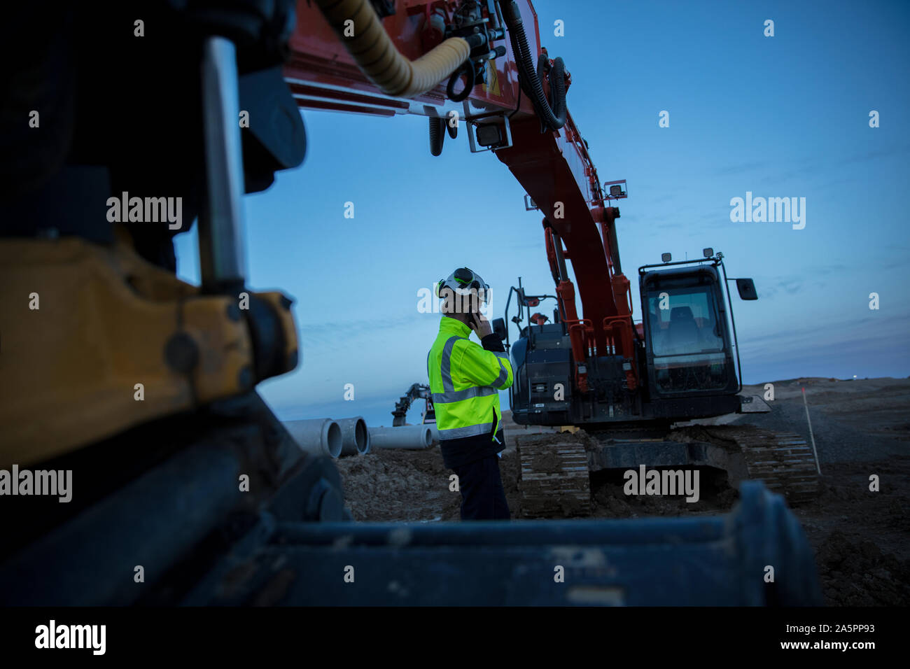 Worker in front of digger Stock Photo - Alamy