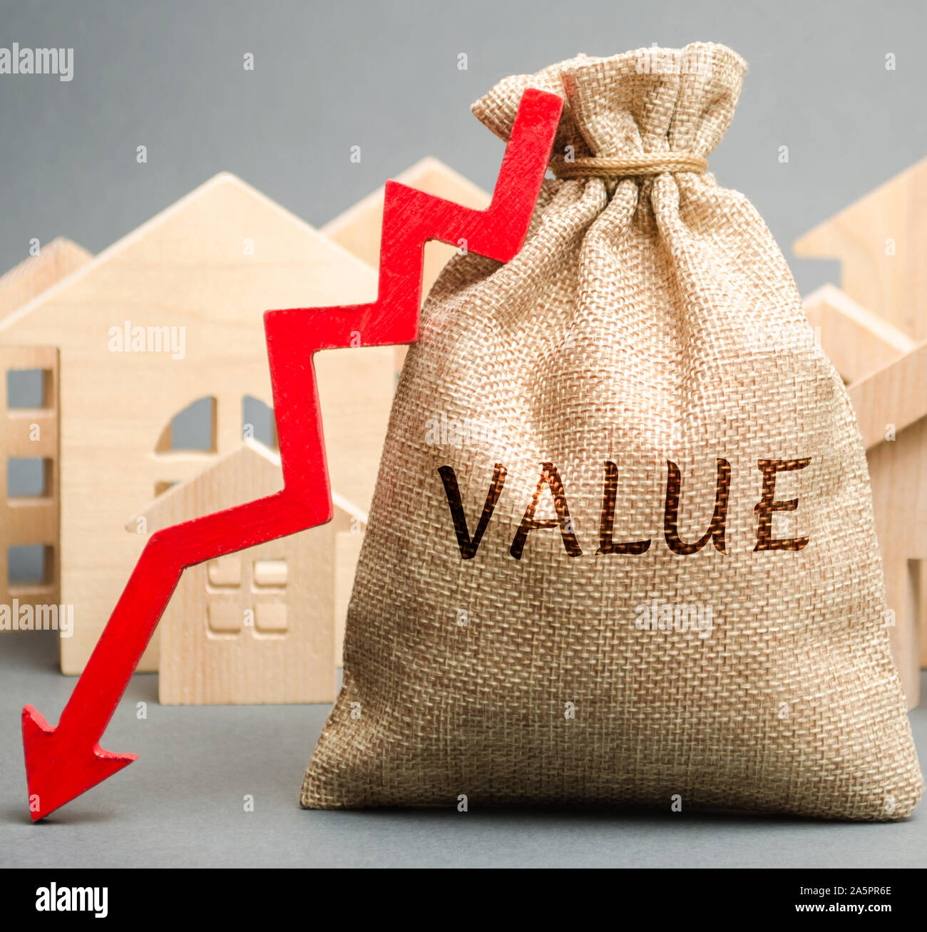 A money bag with the word Value, wooden houses and down arrow. The ...