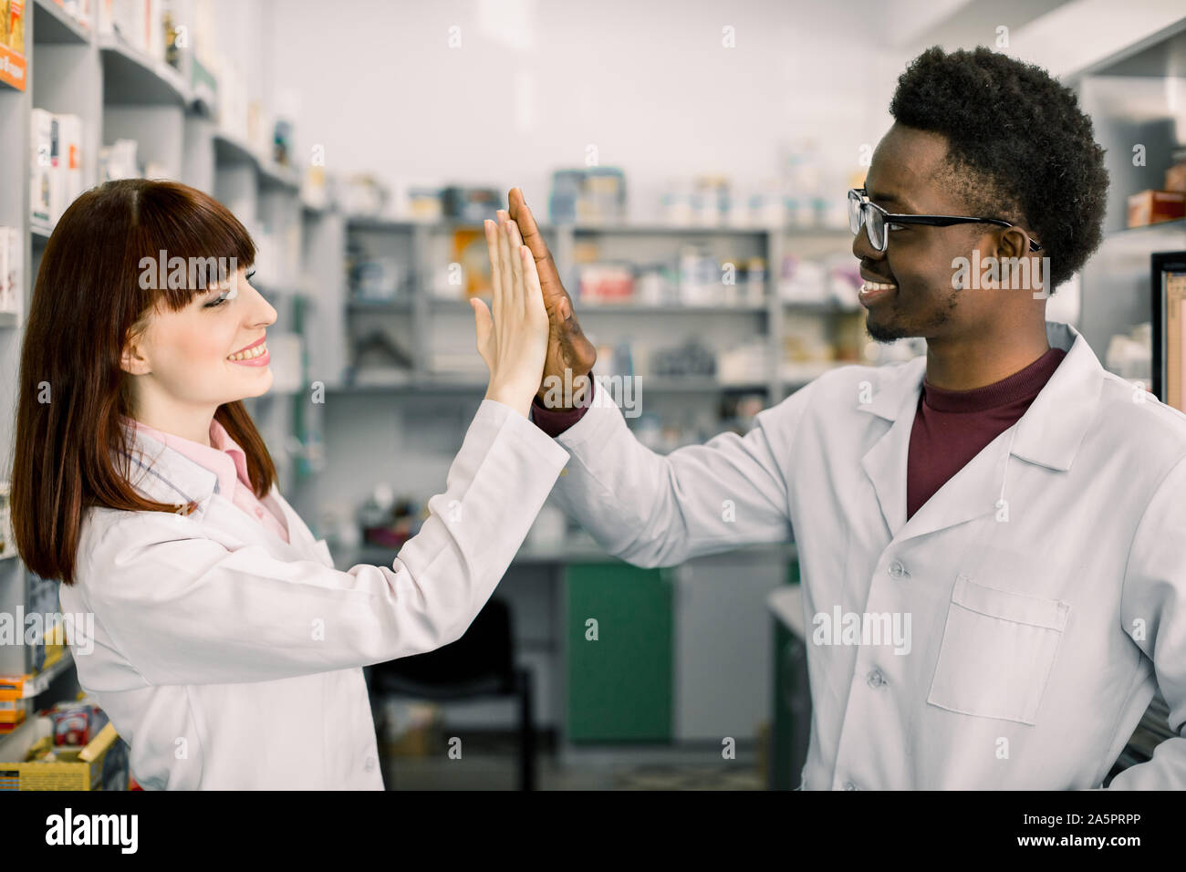 Two happy colleages pharmacists, African man and Caucasian woman ...