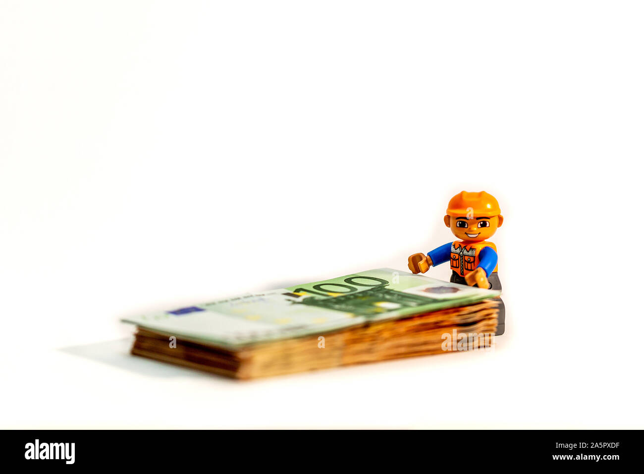Minifigure toy worker model standing of a pilo of euro banknote, money ...