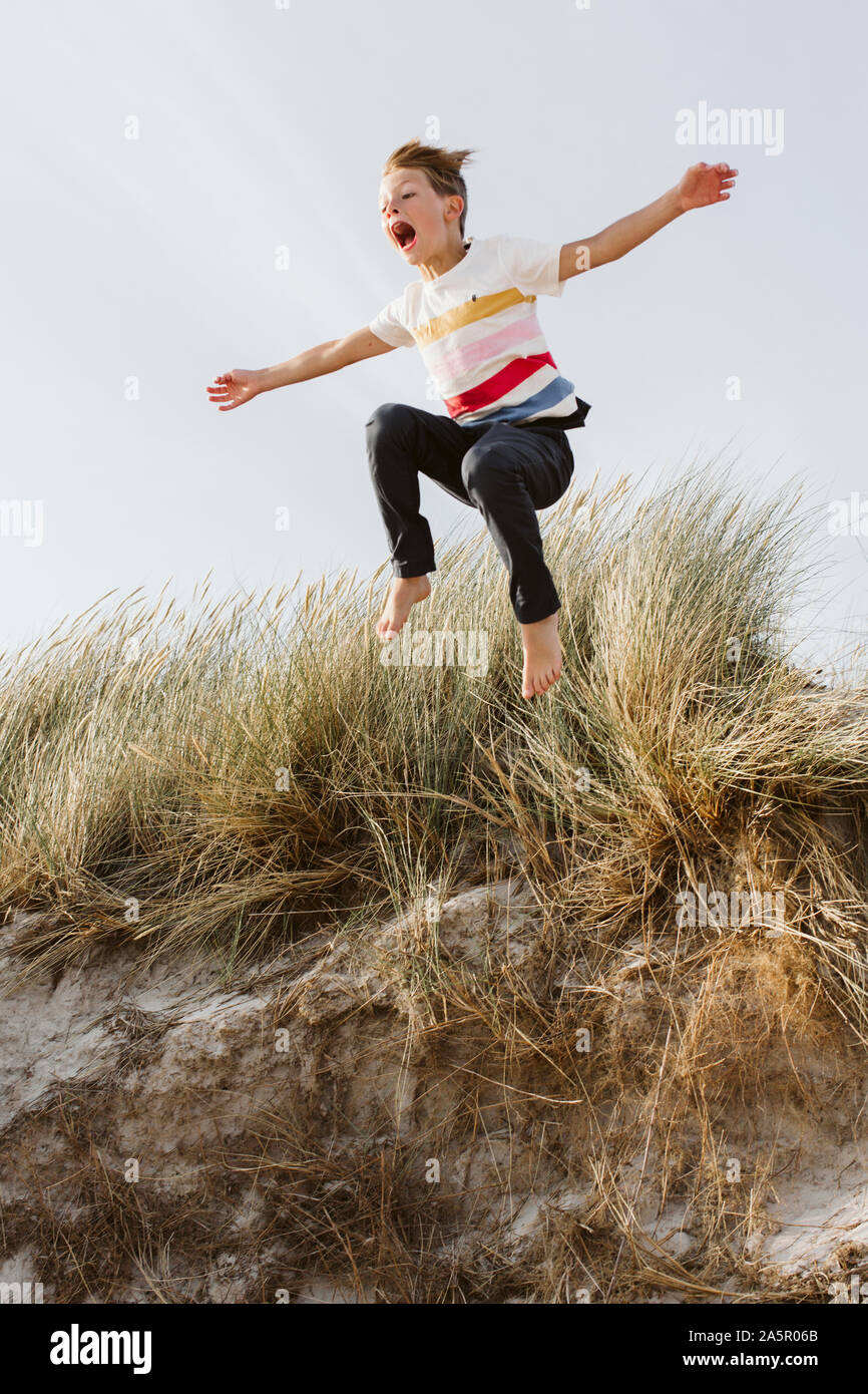 Boy jumping on sand dune Stock Photo - Alamy