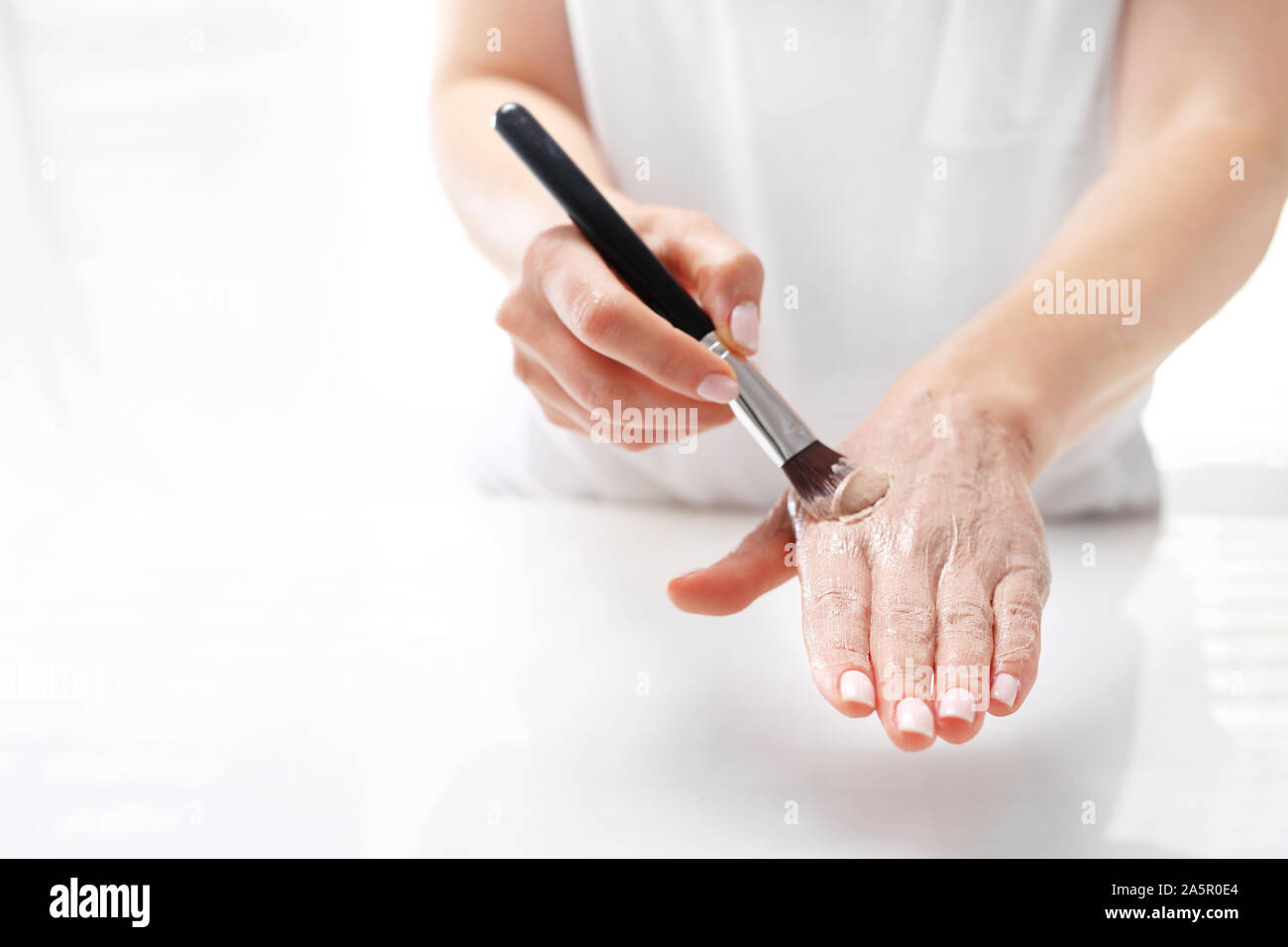 Hand spa. The woman puts a mask on the skin of the hand. Hand skin care ...