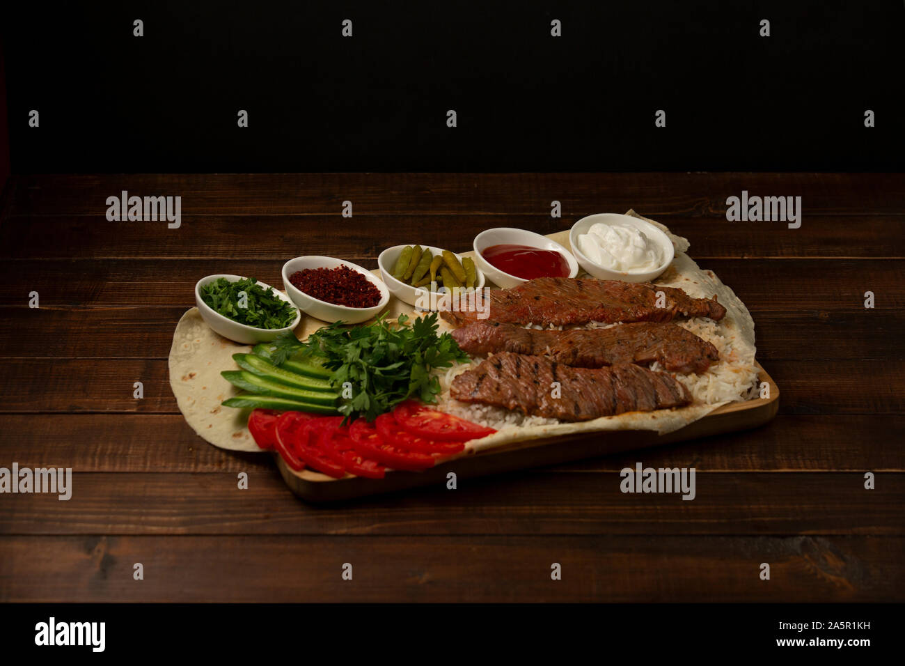 beef fillet kebab slices on rice, served with tomato, cucumber, herbs ...