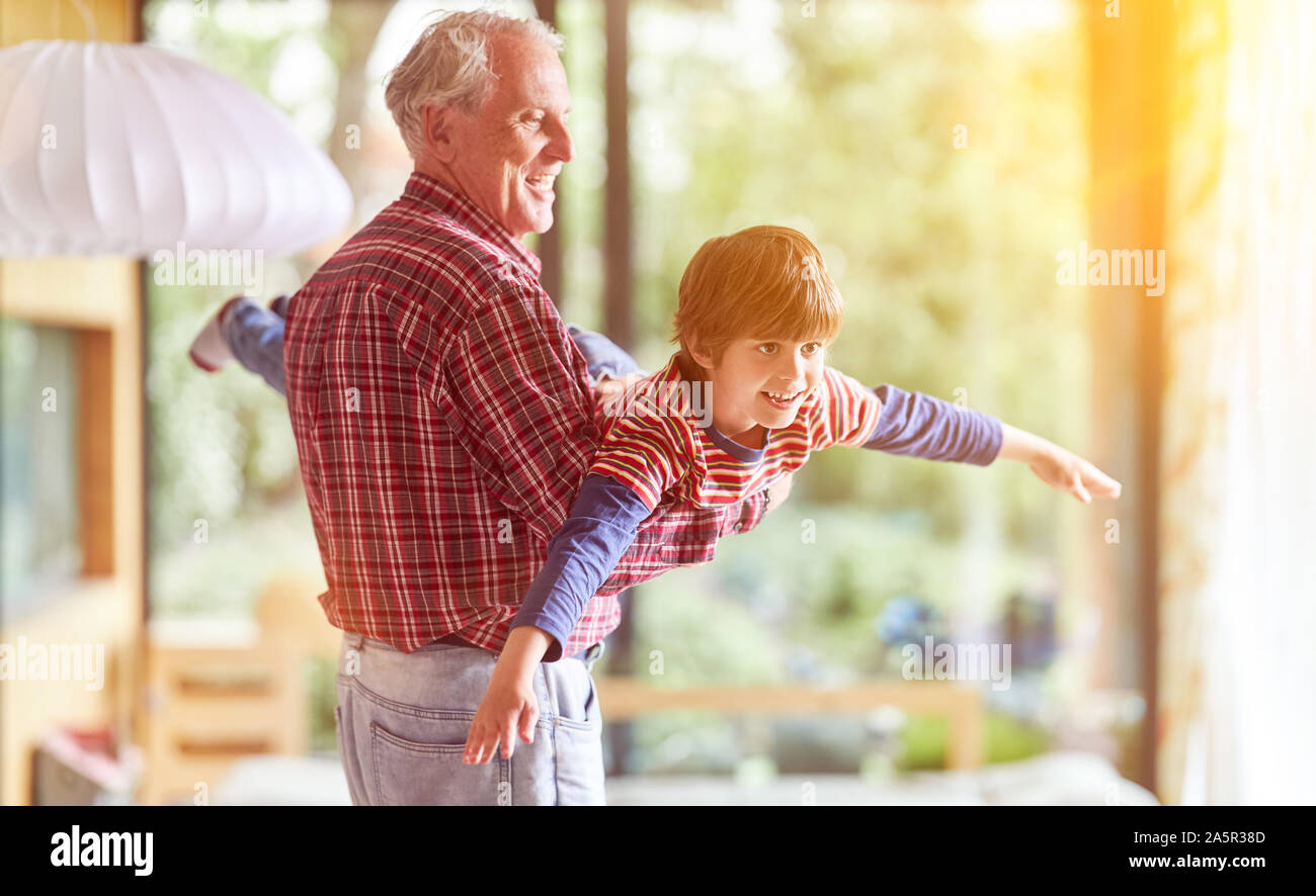 Grandpa plays with his happy grandson at home in the living room and ...