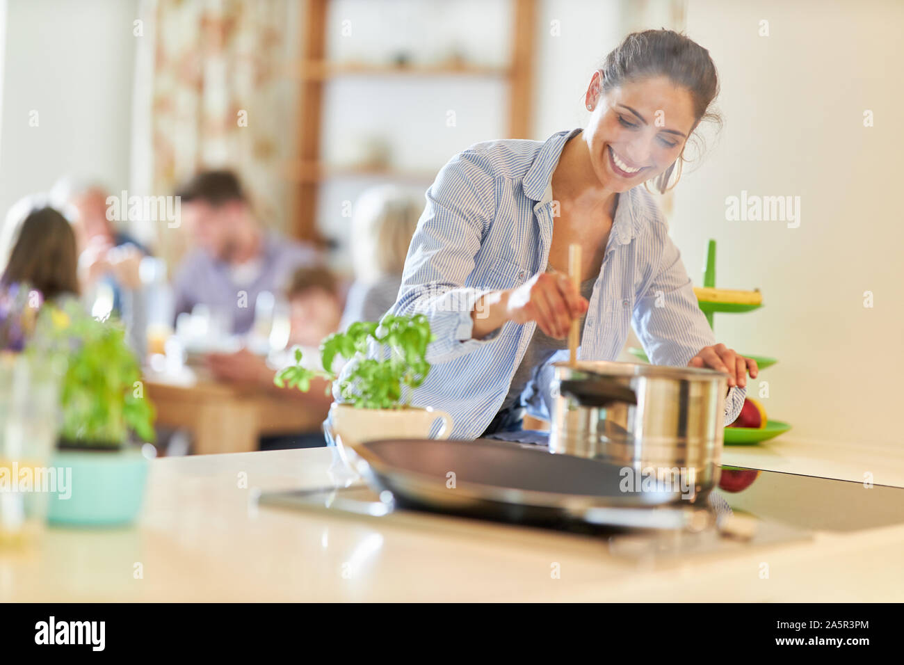 Woman cooking at the stove as a housewife and hobby cook stirs in a ...