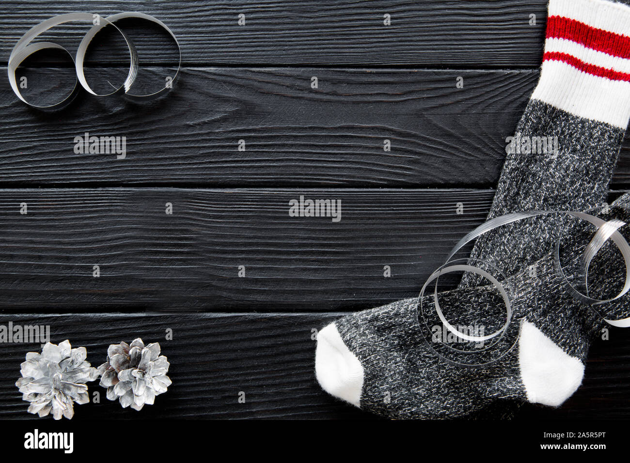 Christmas socks on black wooden table. Silver cones, ribbons and ...