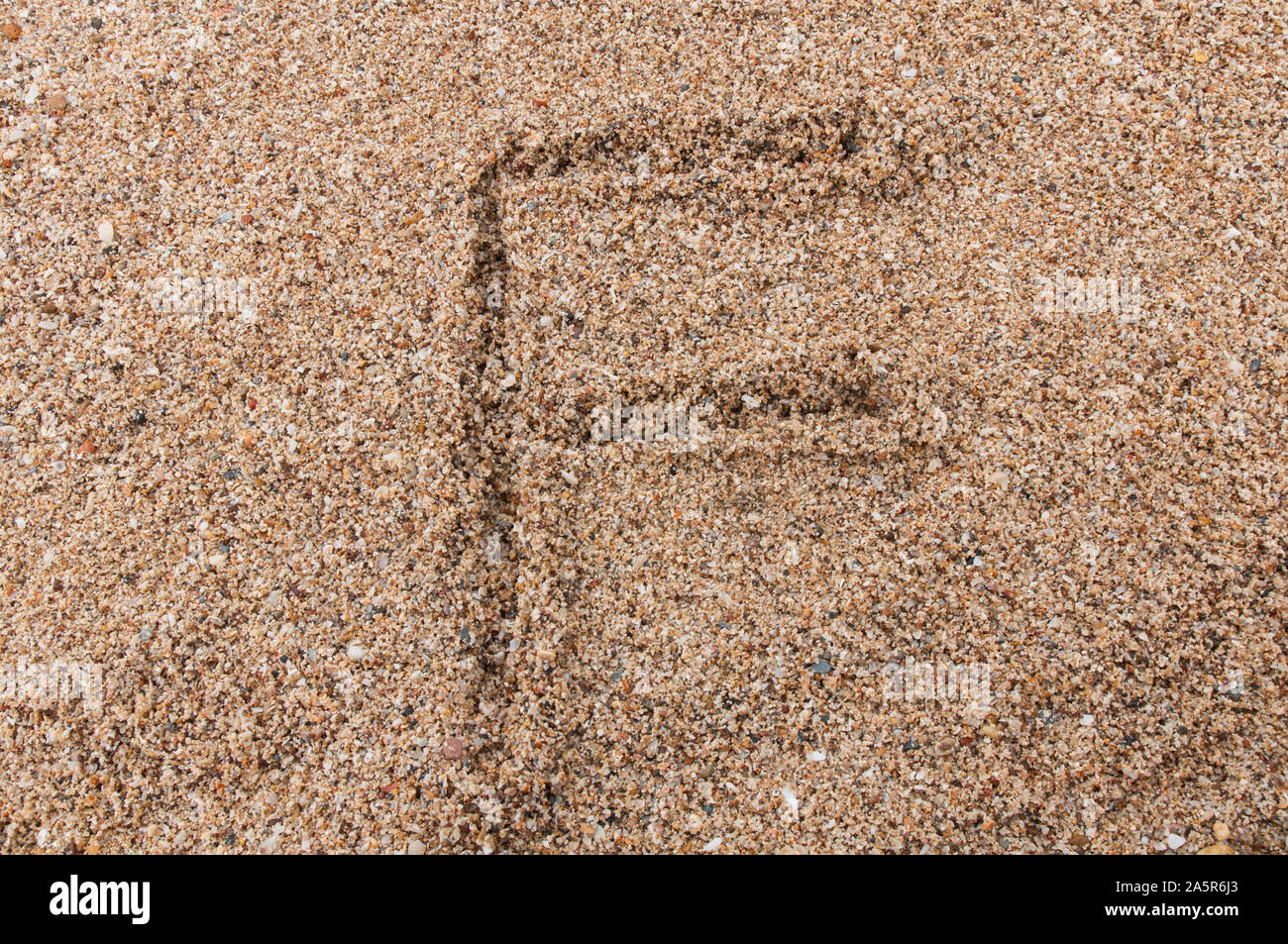 Character F of the alphabet writing on the sand Stock Photo - Alamy