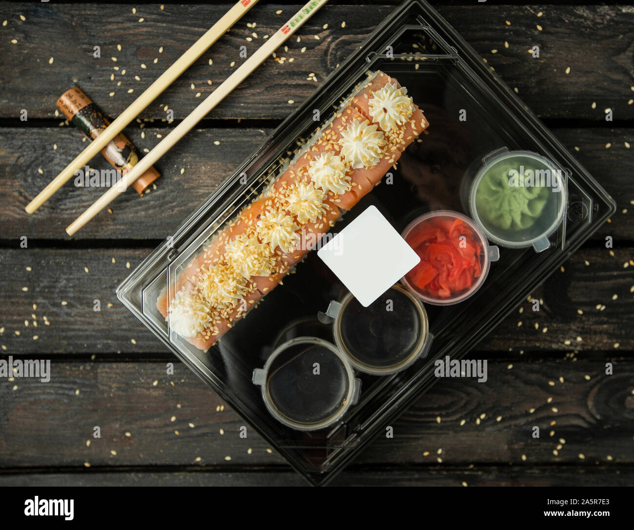 plastic box of shushi rolls for delivery with salmon, sauces, wasabi ...