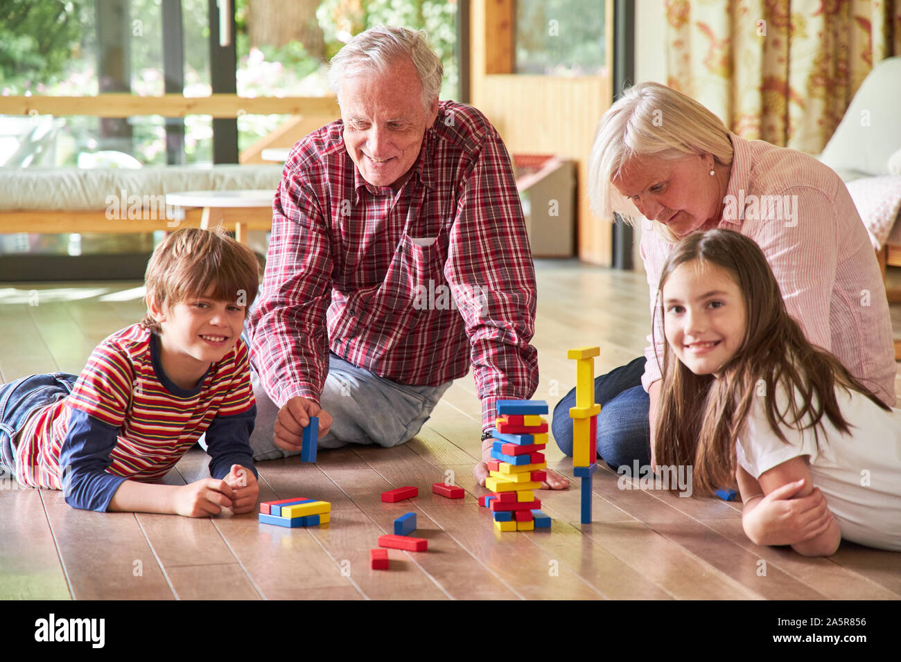 Family with grandparents and children build a tower together with ...