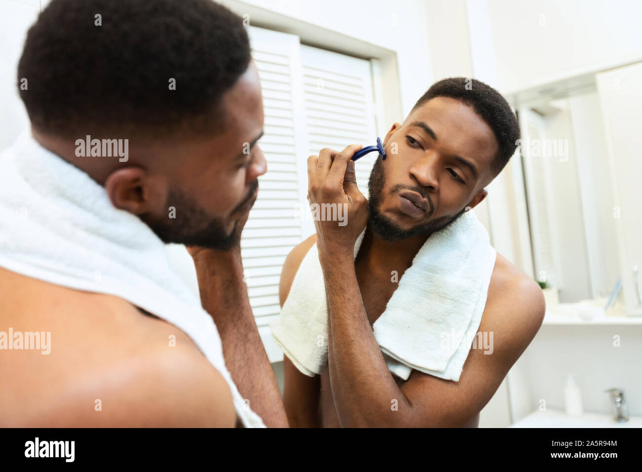 Black millennial guy shaving his beard in bathroom Stock Photo - Alamy