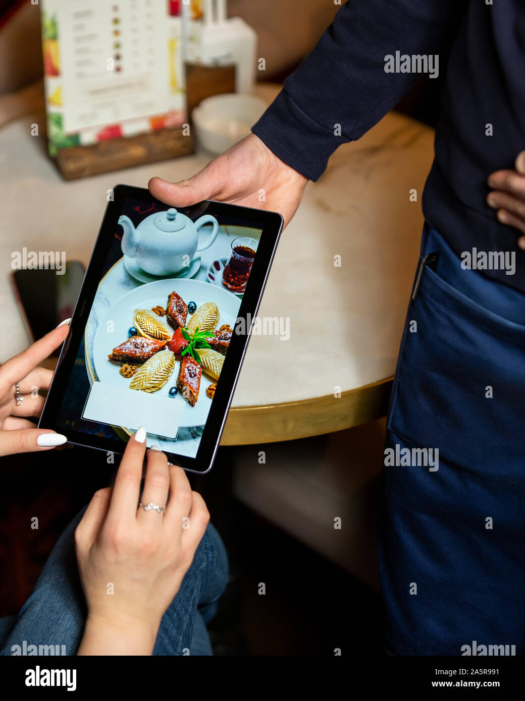 waiter shows dessert menu on tablet to customer at the restaurant Stock ...