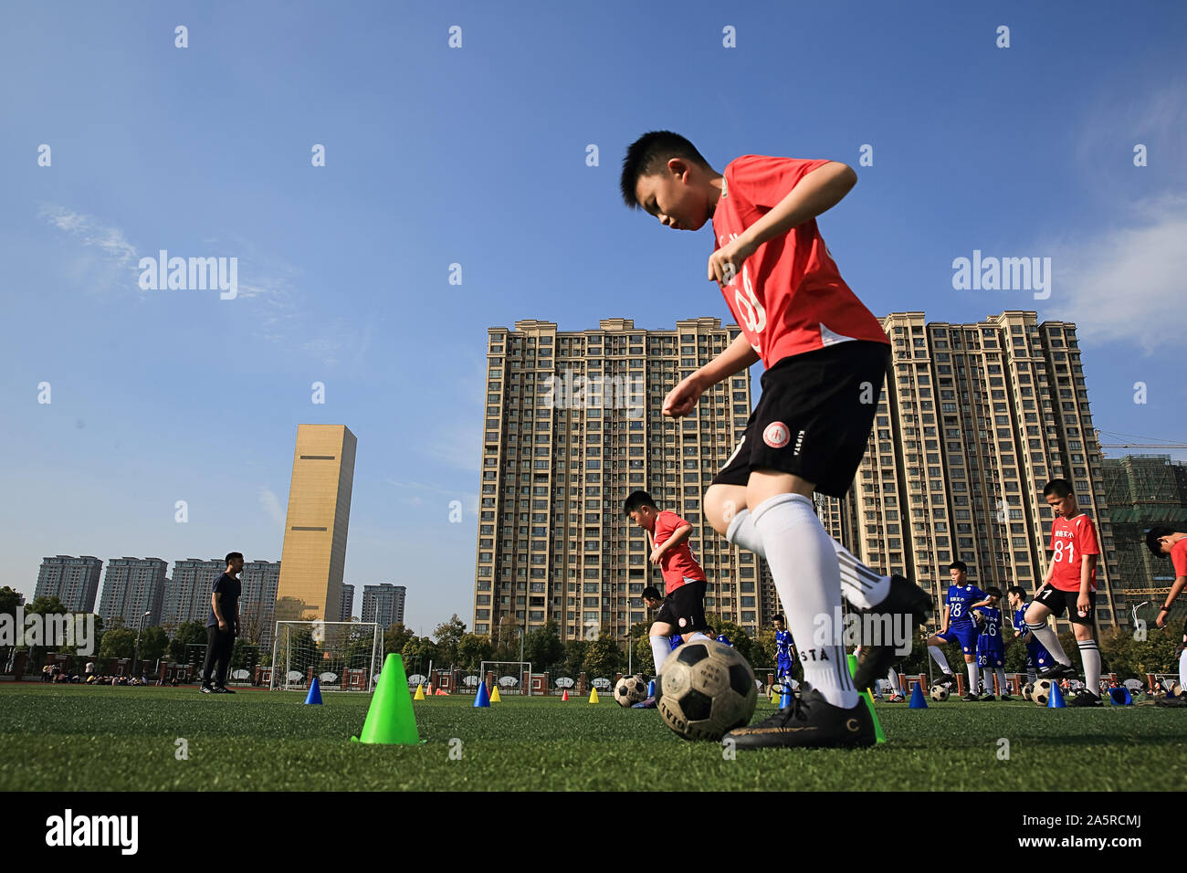 Young Chinese students practice football on the court at a primary ...
