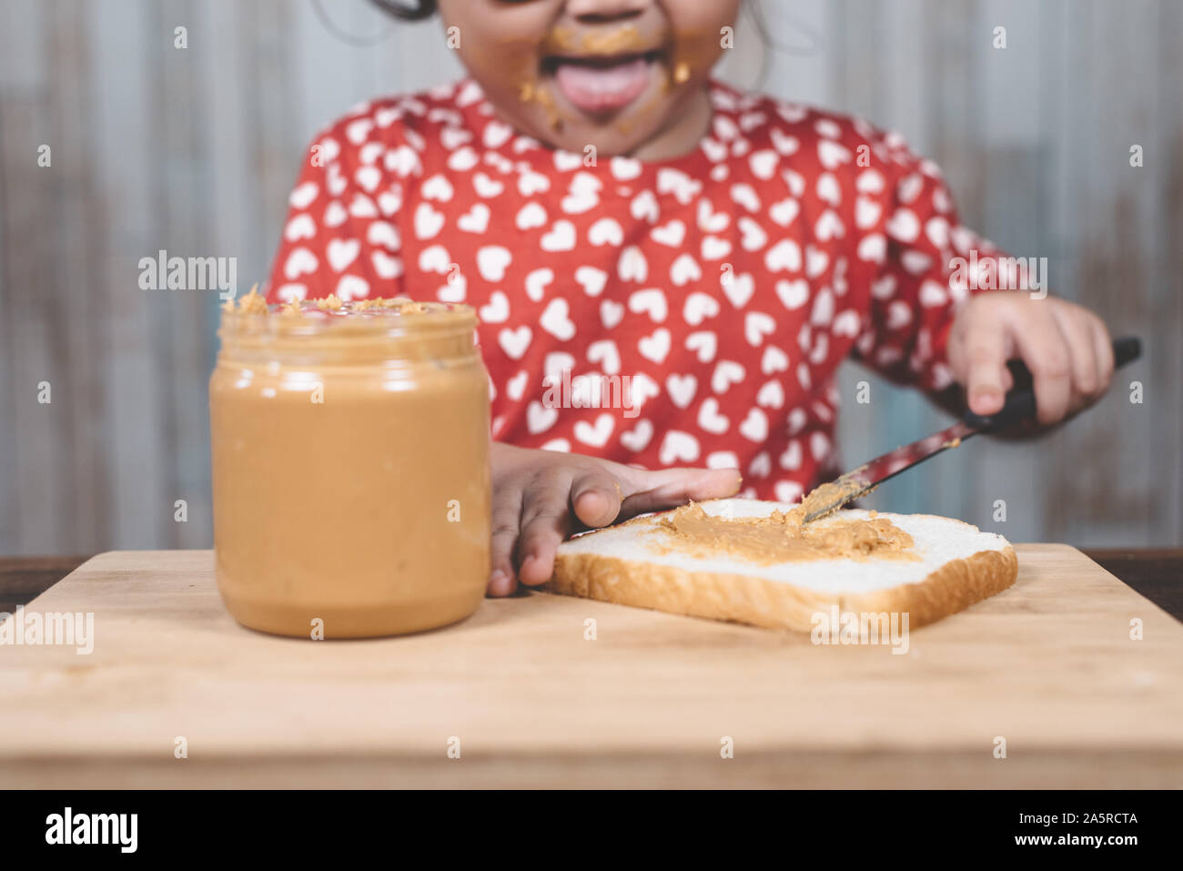 little asian girl spreading a peanut butter on a white bread. Concept ...