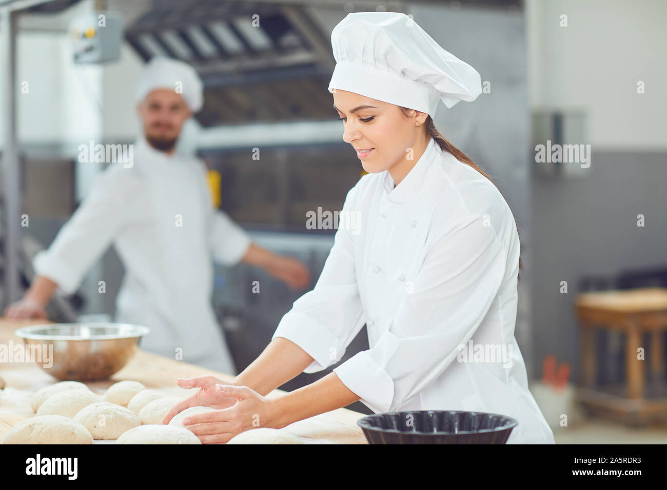 A girl baker smiles with colleagues at a bakery Stock Photo - Alamy
