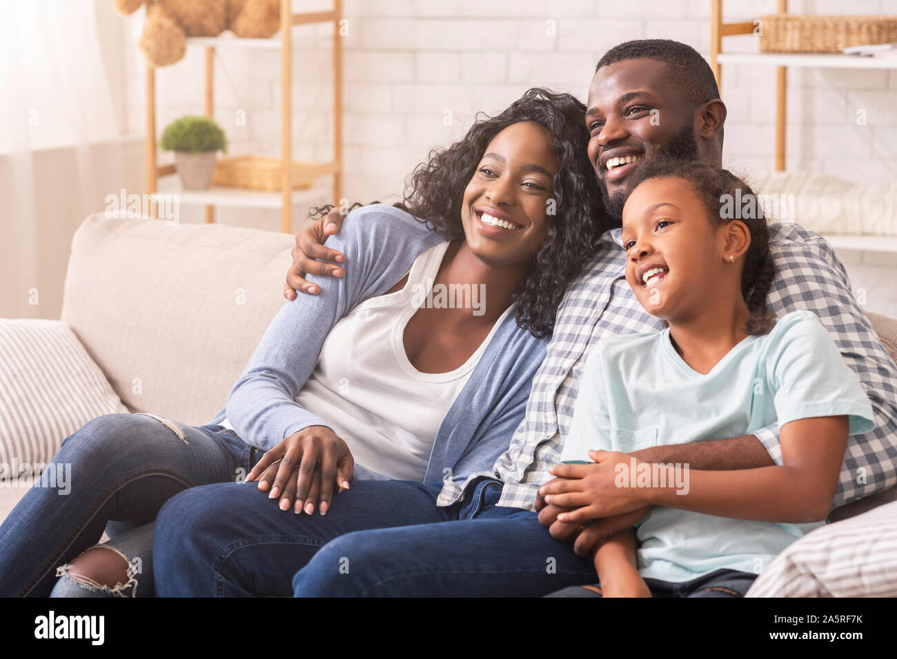Father, mother and daughter watching tv together, relaxing at home ...