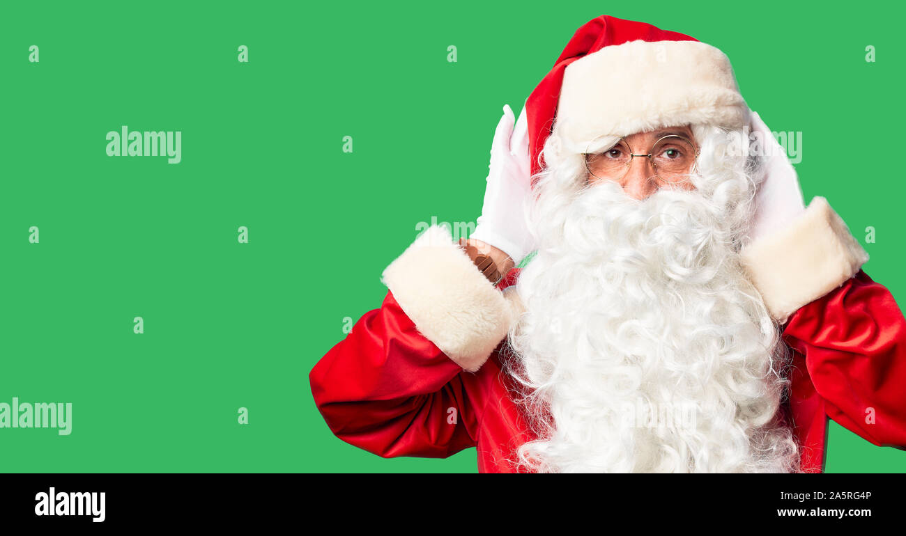 Middle age handsome man wearing Santa Claus costume and beard standing ...