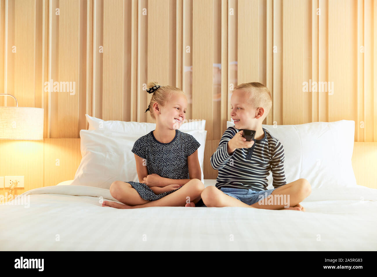 Smiling little brother and sister looking at each other while sitting ...