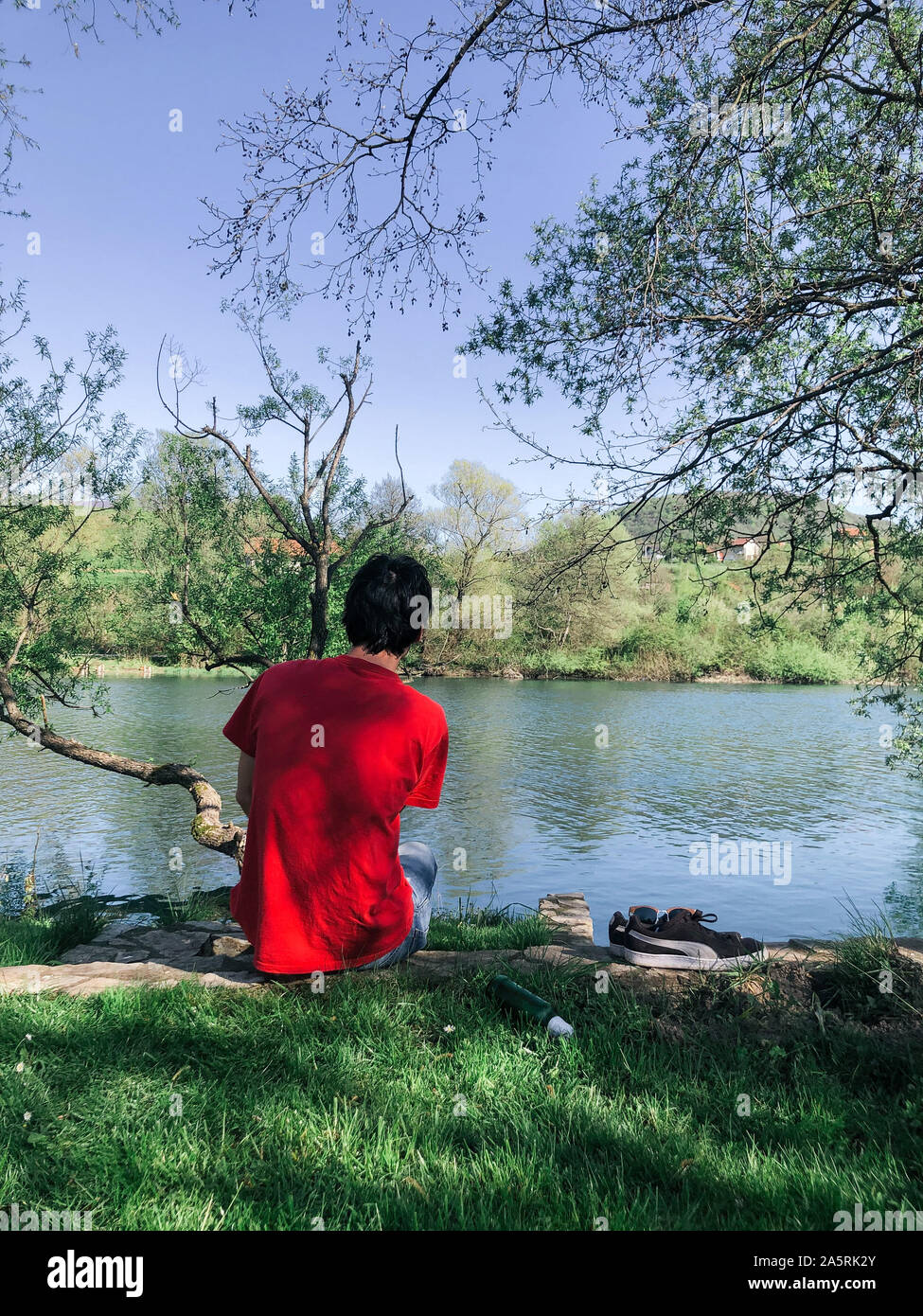 Back view of a man sitting and watching river Stock Photo - Alamy