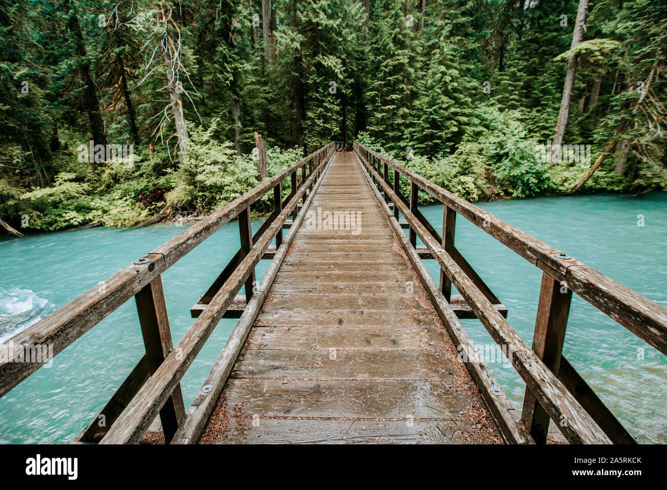 A pedestrian bridge crosses a vibrant blue river, cascades, washington ...