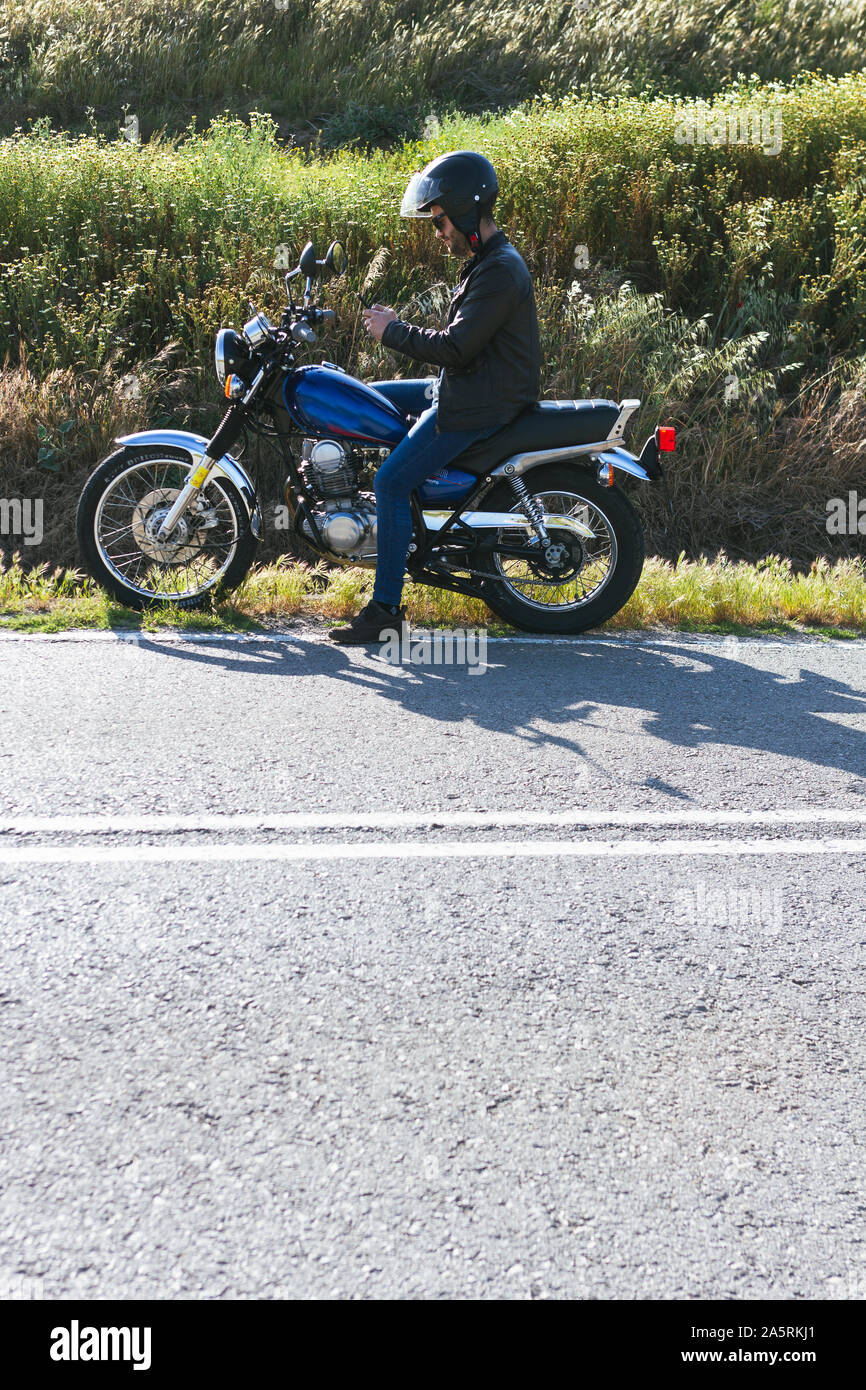 young man looking at the route to follow on his motorcycle with the mo ...