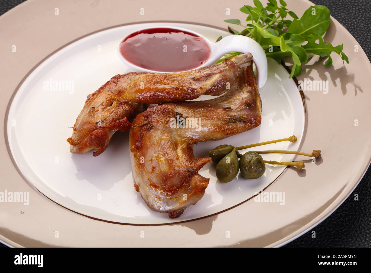 Roasted rabbit legs with cowberry sauce Stock Photo - Alamy