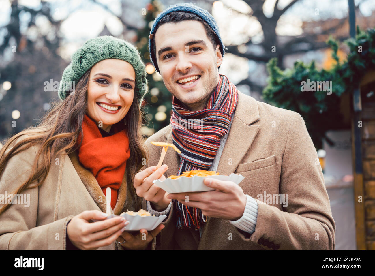 Man and woman eating snacks on a Christmas Market Stock Photo - Alamy