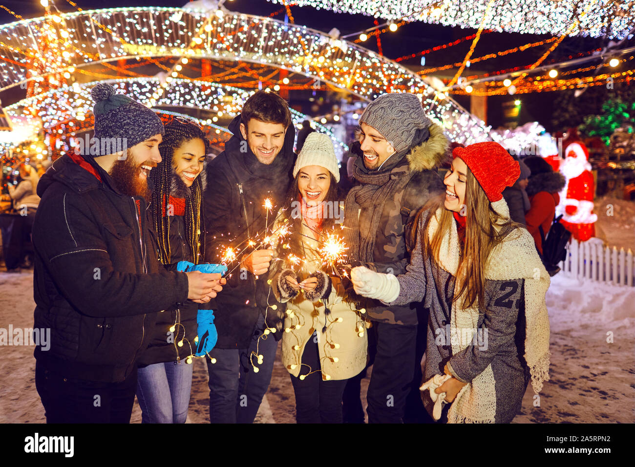 Happy friends with sparklers at a fair at christmas Stock Photo - Alamy