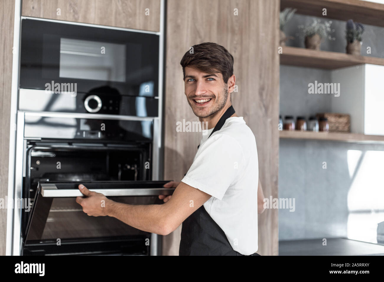 man opening the oven in the home kitchen Stock Photo - Alamy