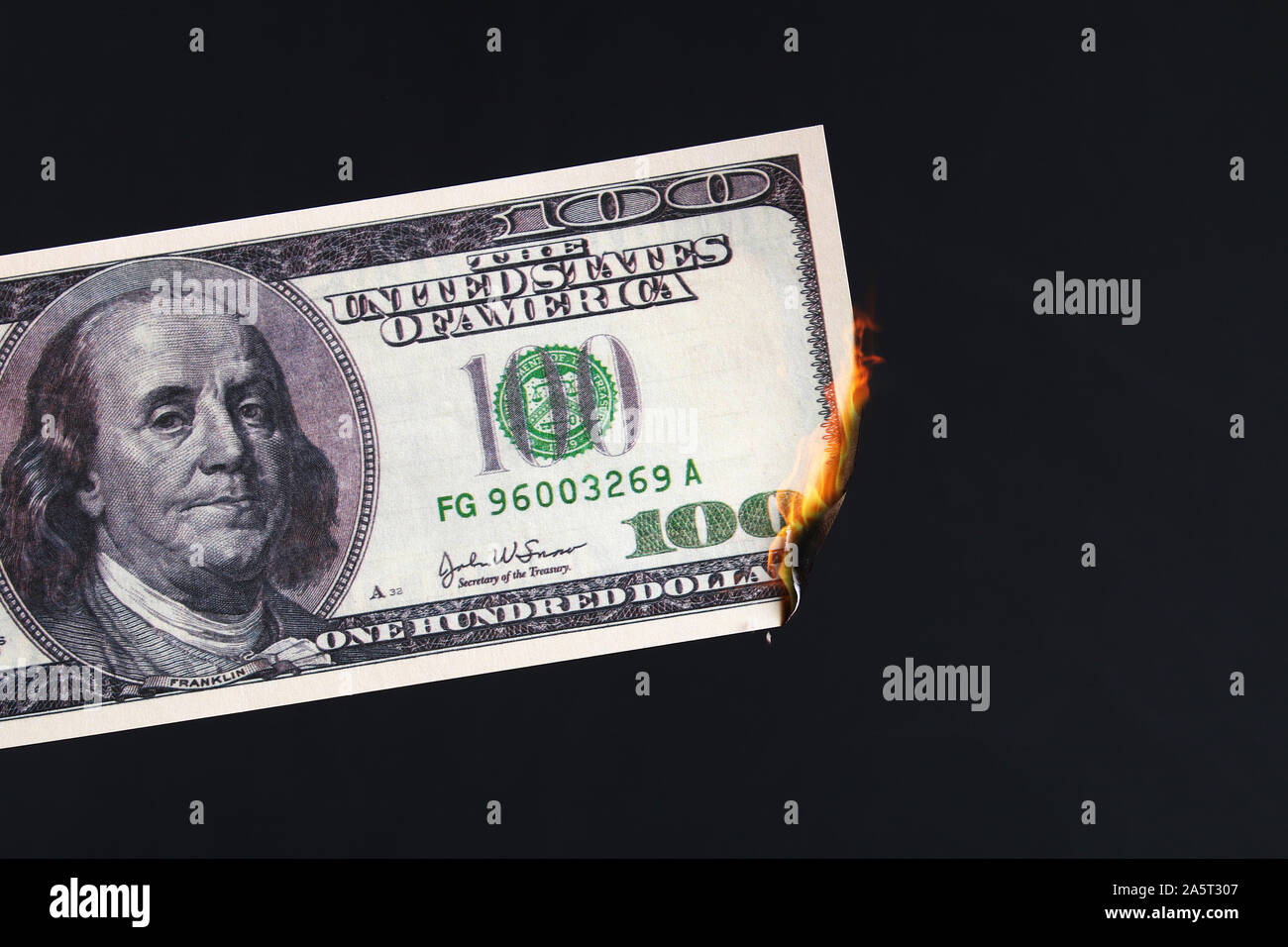 one hundred American dollar burning in fire flame on black paper ...