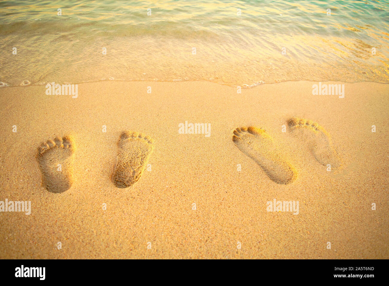Feet prints on the sand of the beach with sea wave. Top view. Two ...