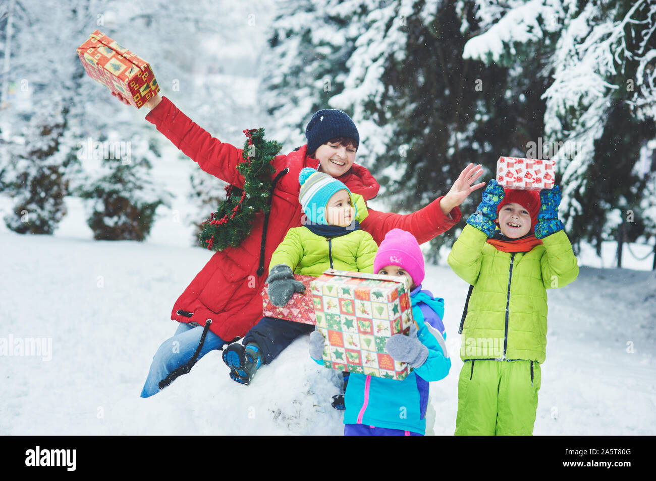a happy family. mother and three children playing in the winter forest ...