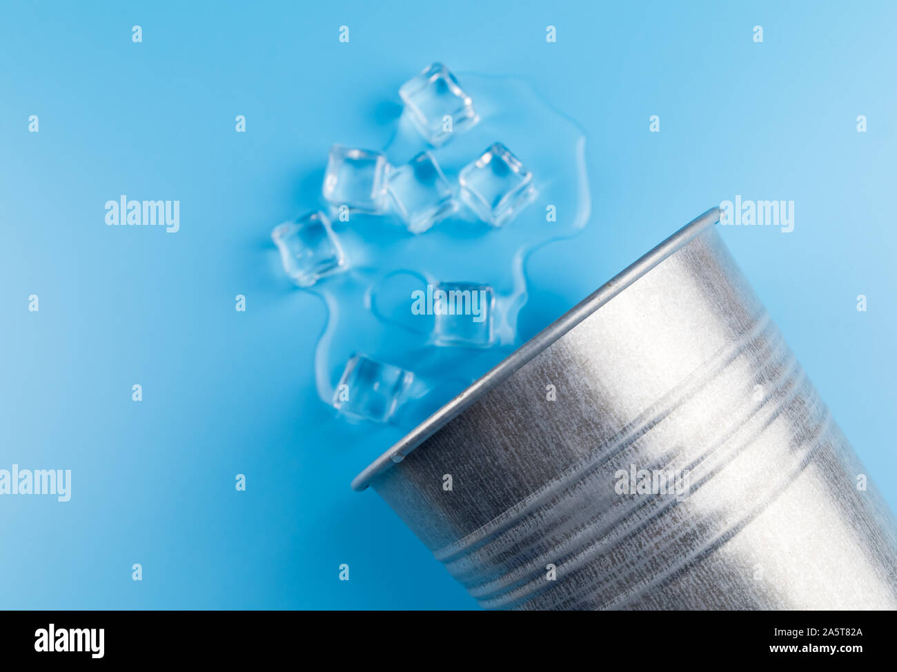 melting ice and metal bucket on blue background Stock Photo - Alamy