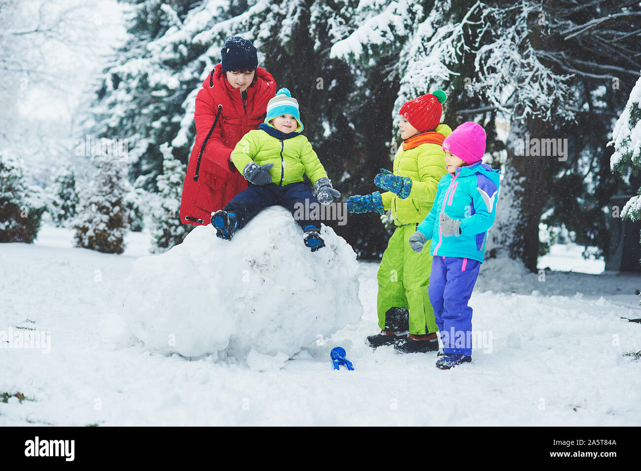 a happy family. mother and three children playing in the winter forest ...
