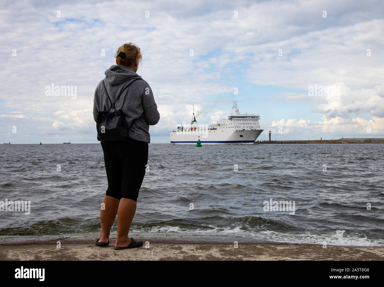 merchant ship entering the Baltic port in Poland,woman on the sea shore ...