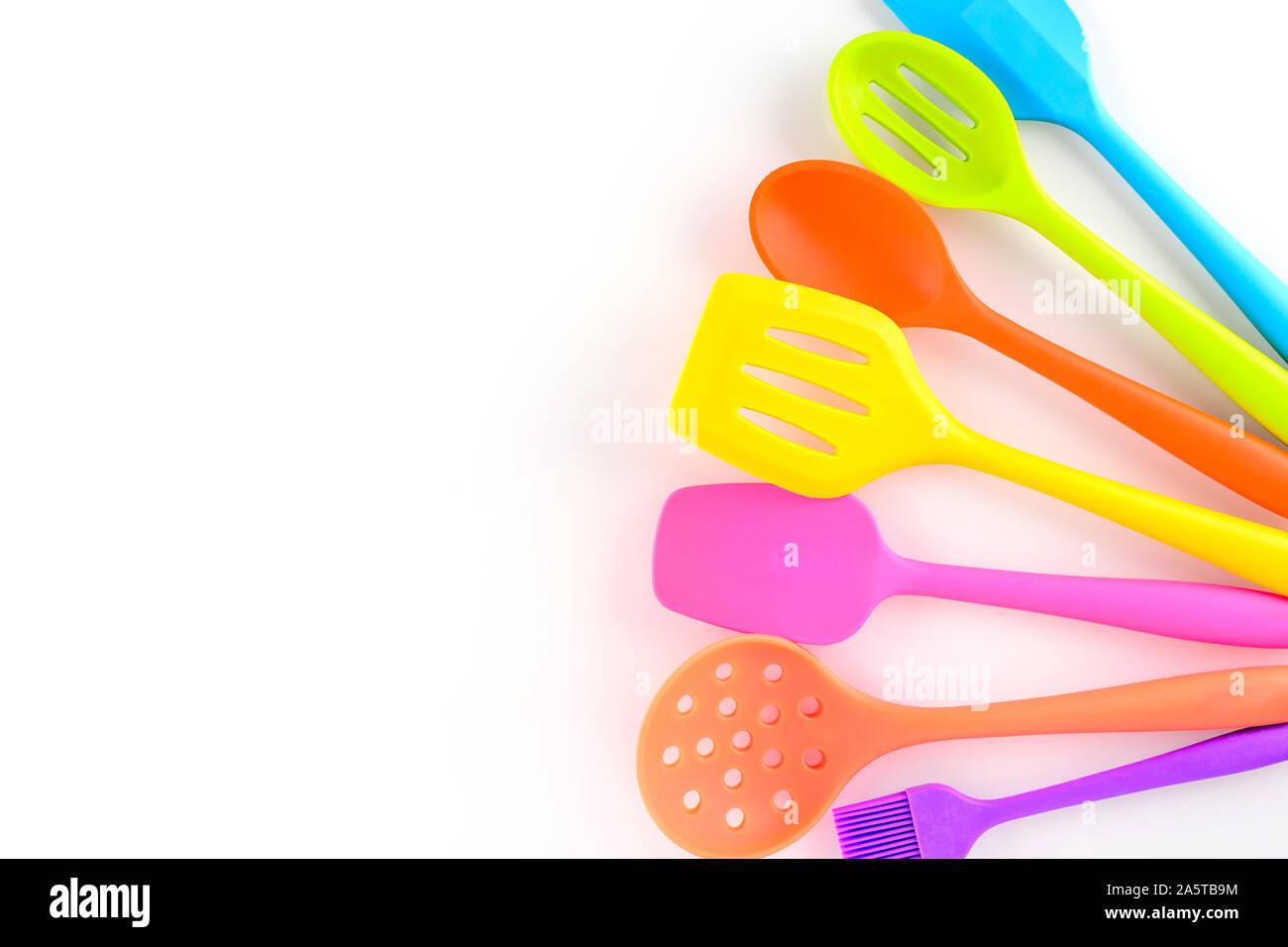 bright multi colored kitchen utensils on white background with copy ...